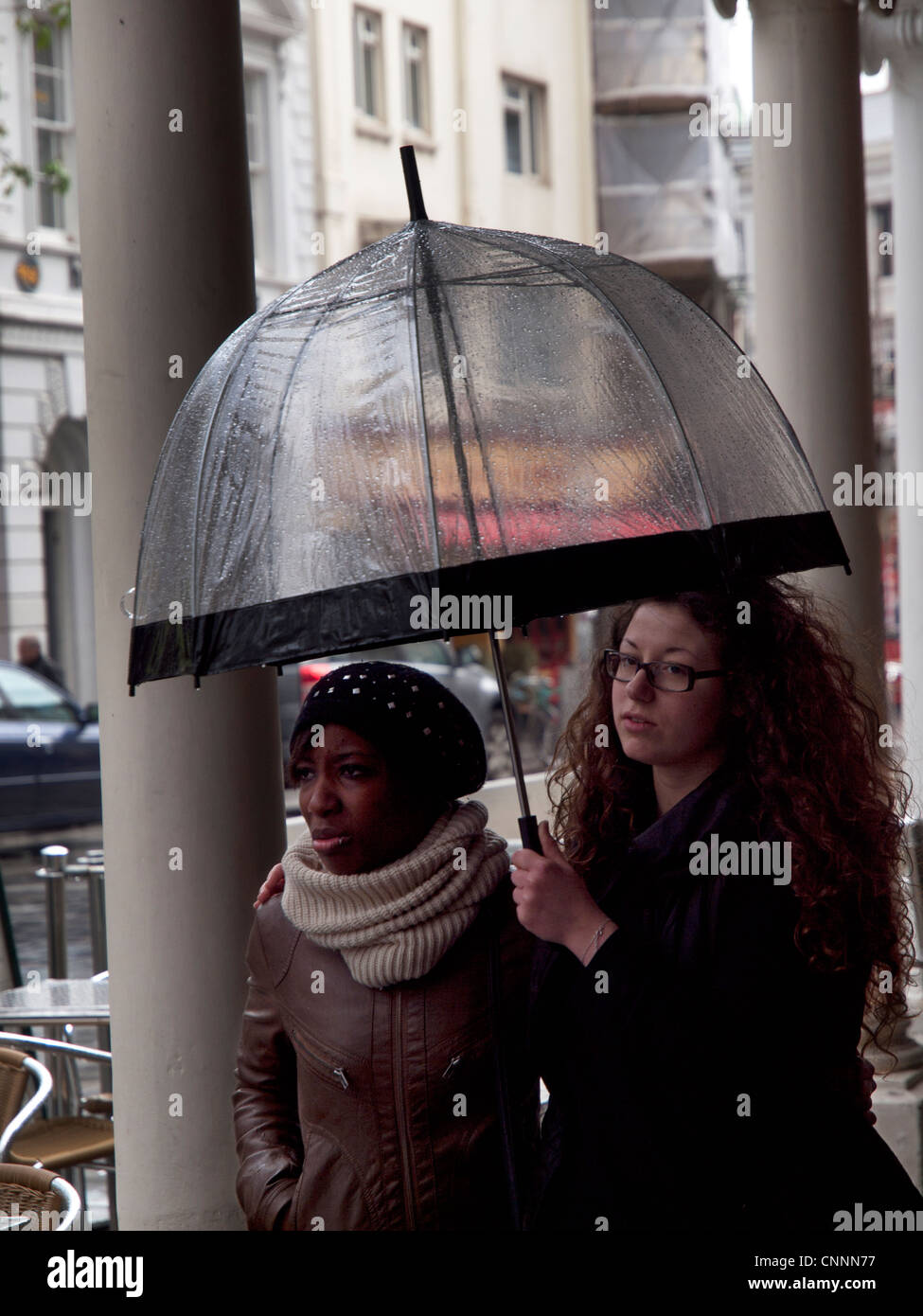 Two friends struggle through the rain Stock Photo - Alamy