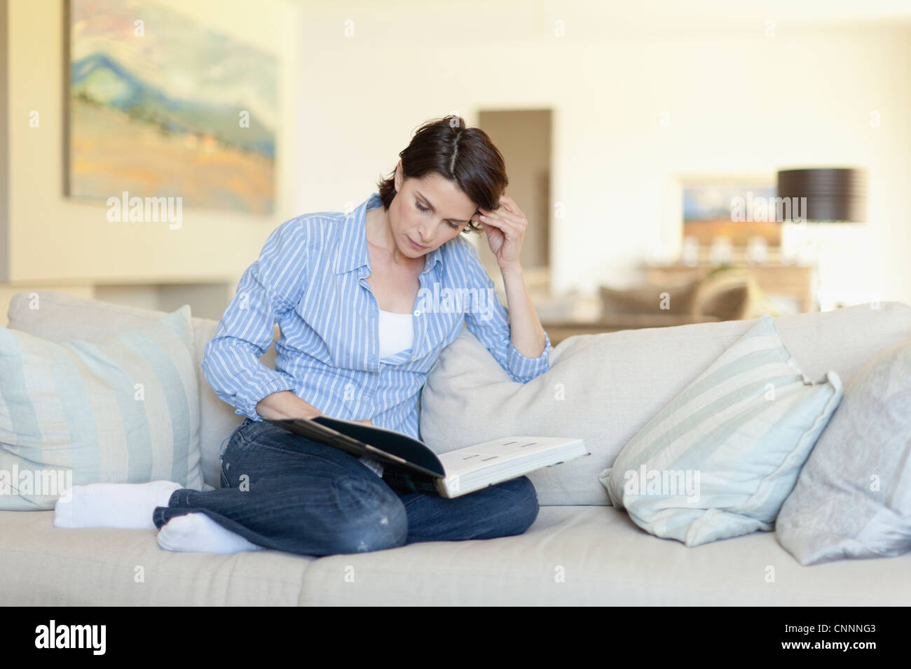 Woman reading on couch Stock Photo - Alamy