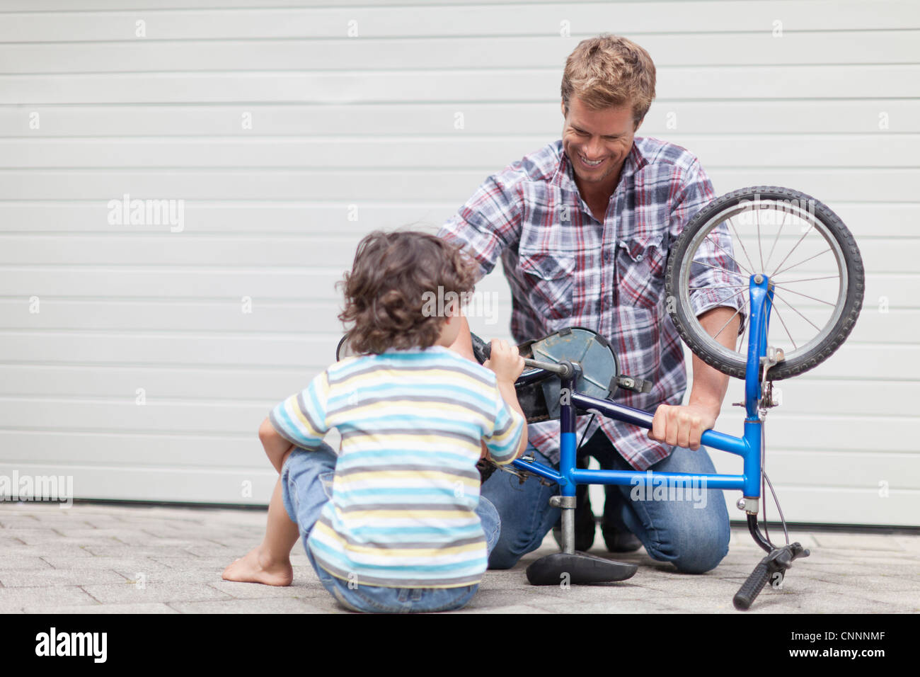 Father helping son fix bicycle Stock Photo - Alamy