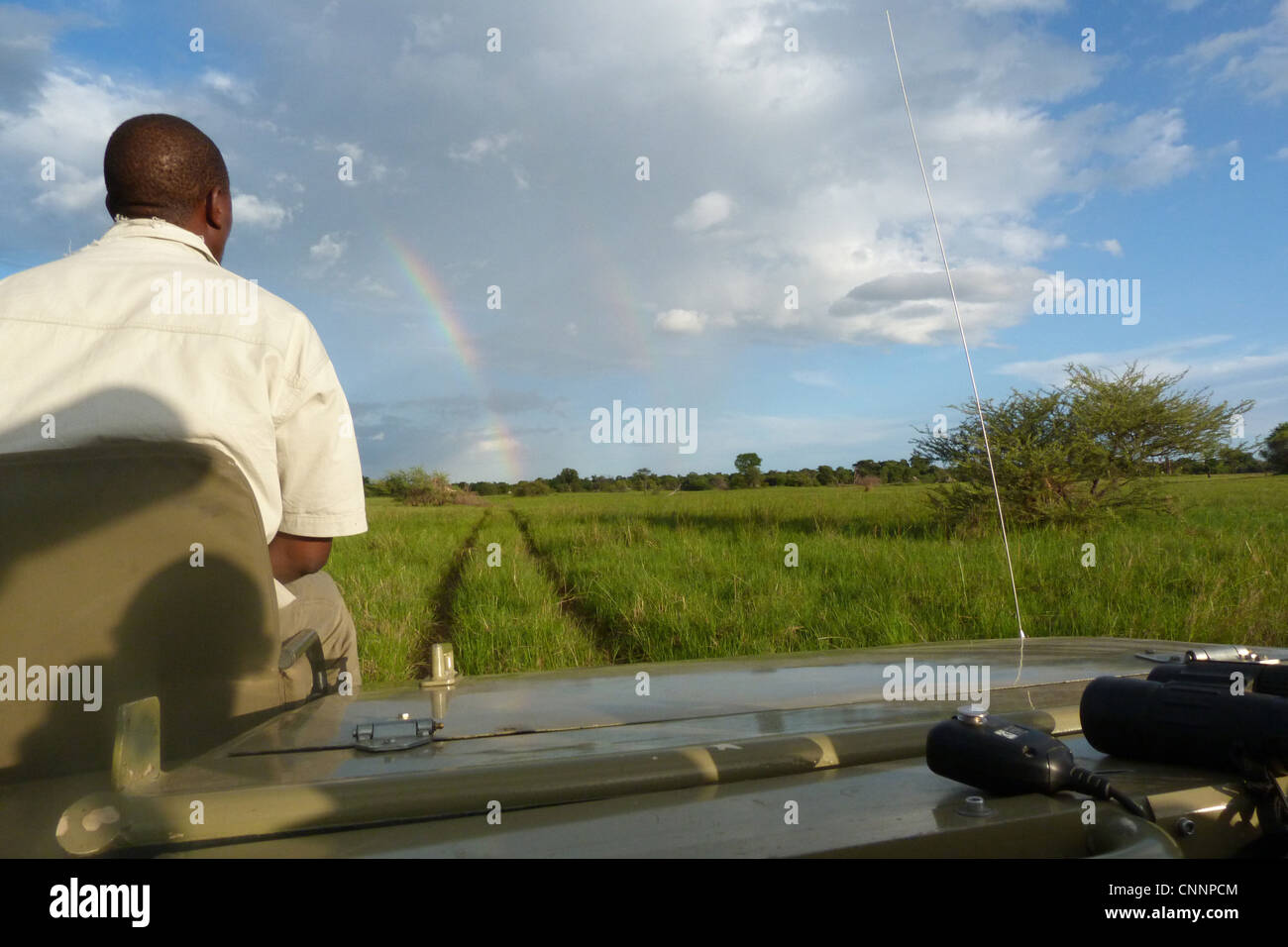 'Spotter' sitting at front of safari vehicle, in wetland habitat with ...