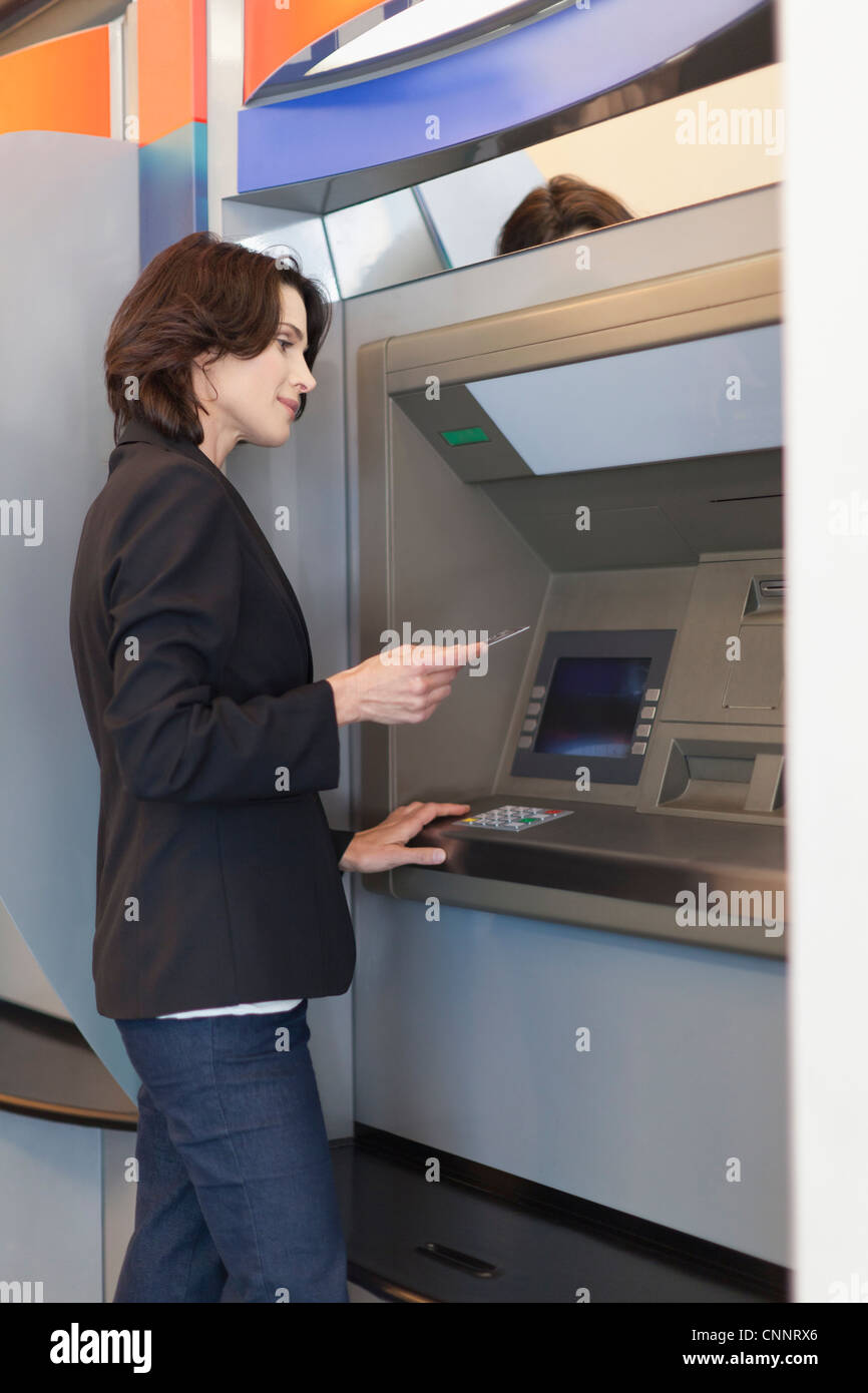 Businesswoman using ATM outdoors Stock Photo - Alamy