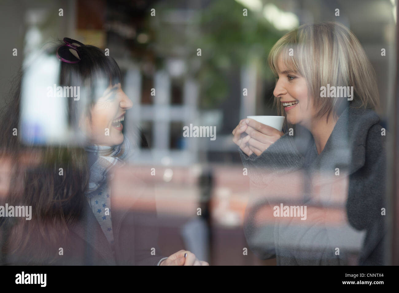 Smiling women having coffee in cafe Stock Photo - Alamy