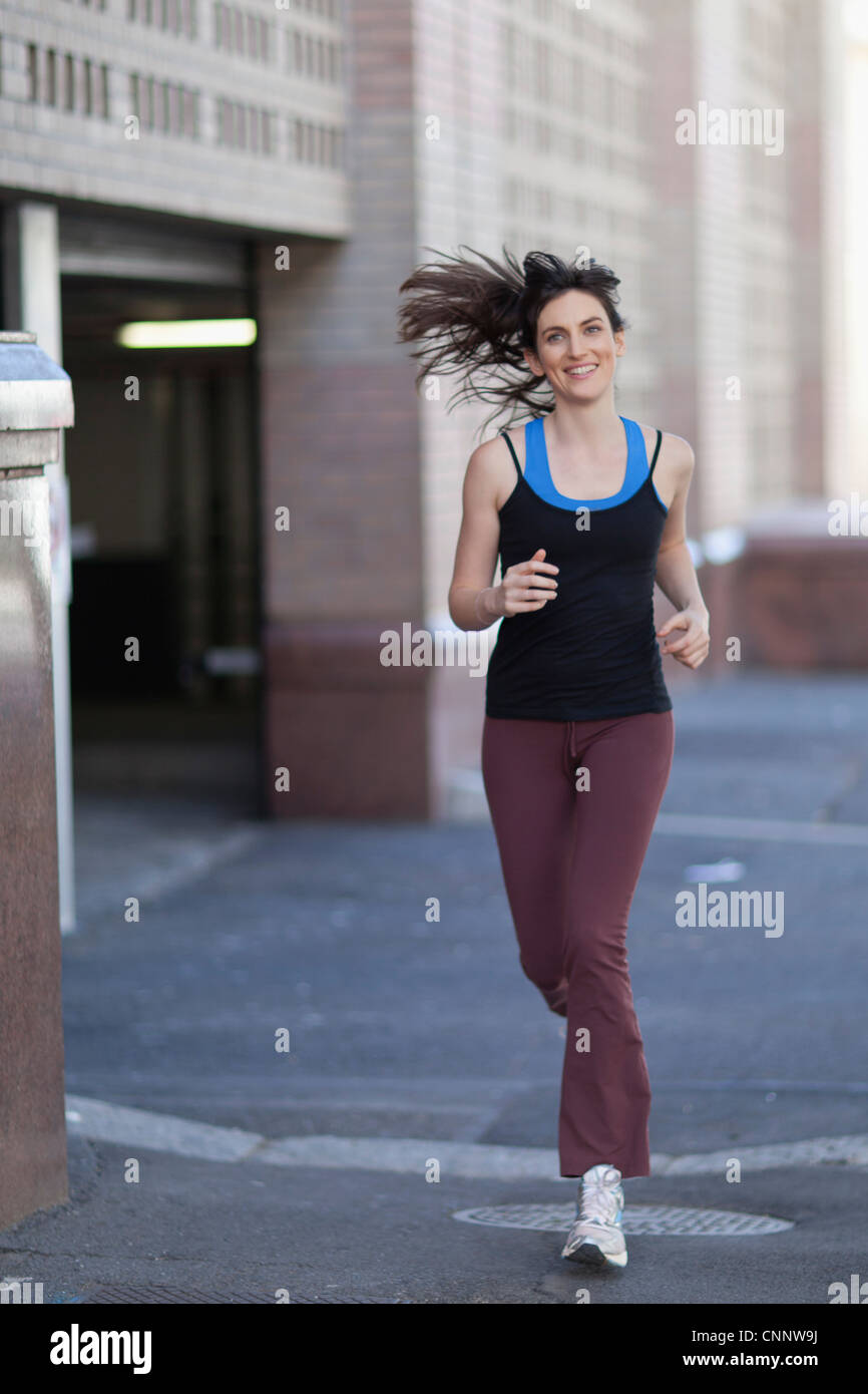 Woman running on city street Stock Photo - Alamy