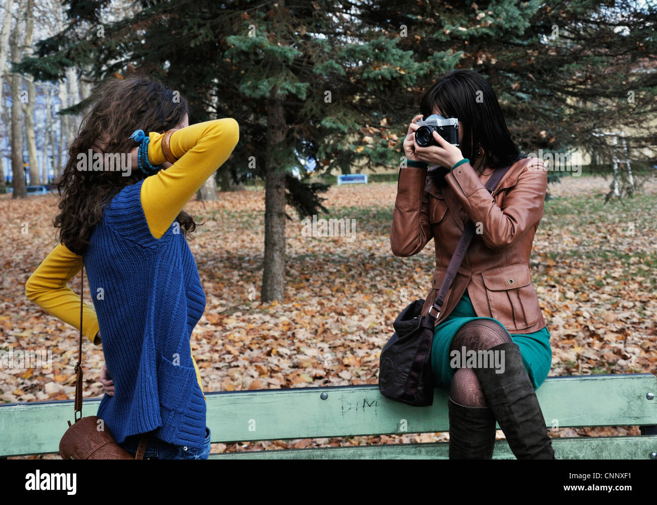 Young woman photographing her friend in park Stock Photo - Alamy