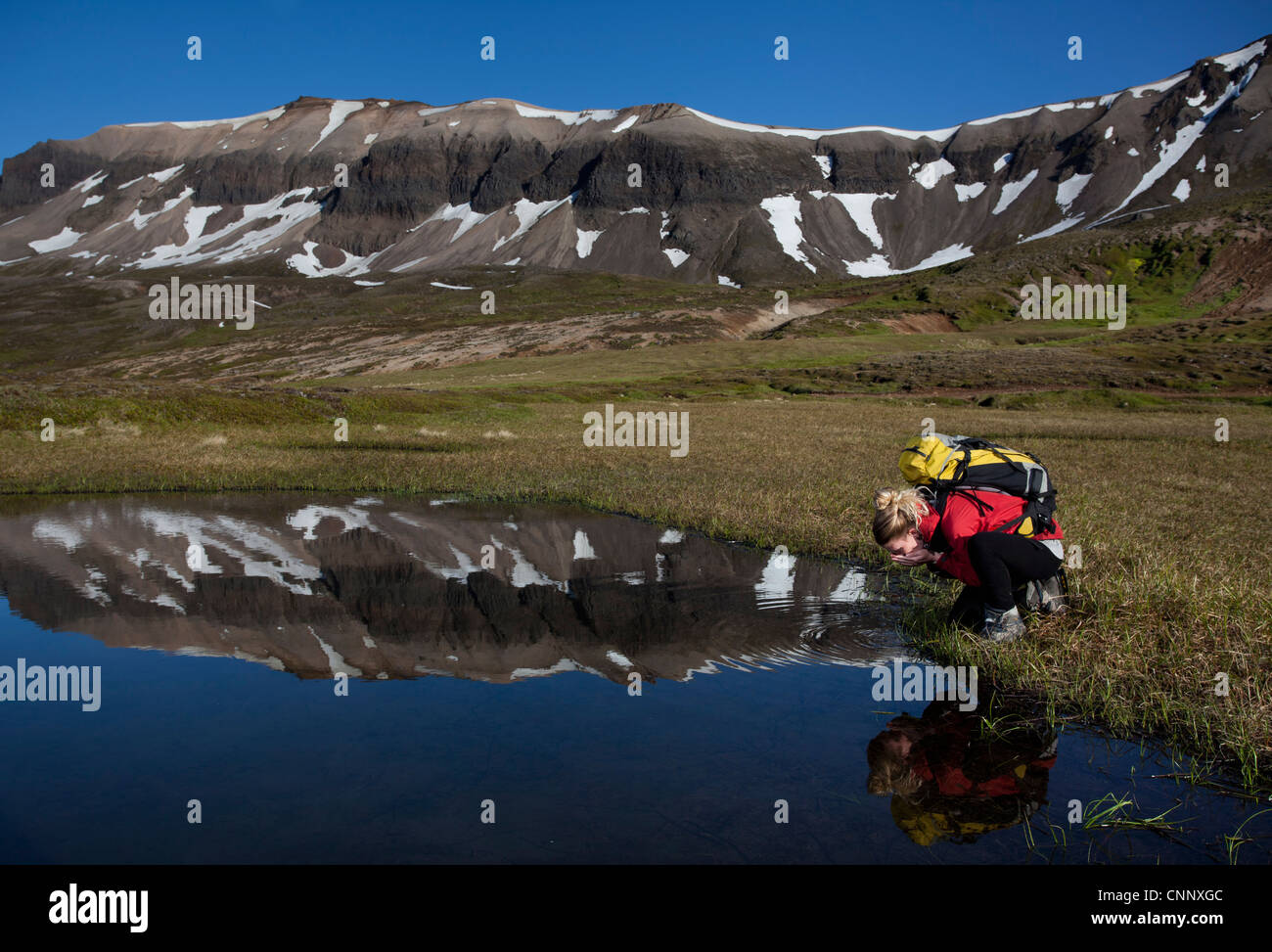 Hiker admiring reflection in still pond Stock Photo - Alamy
