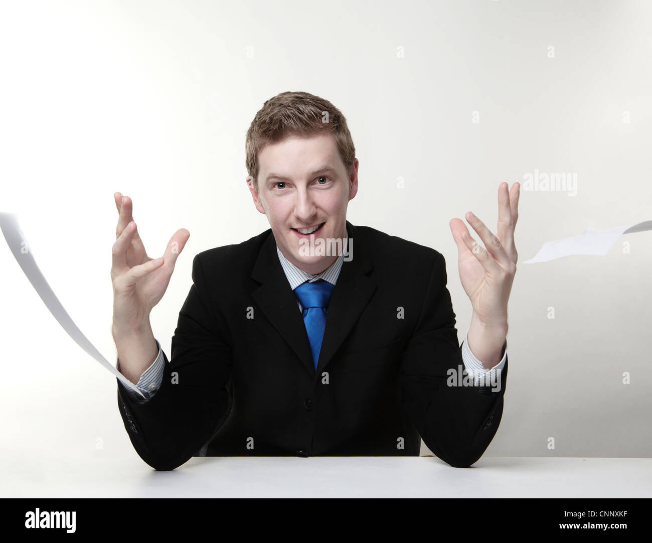 man in a suit sat at a desk just ripped up a piece of paper up with the ...