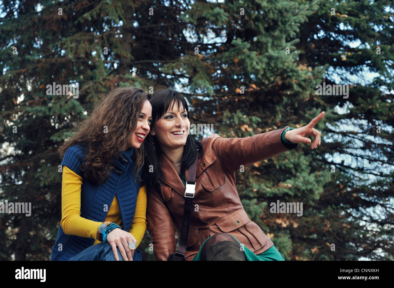 Two young women outdoors laughing and pointing Stock Photo - Alamy