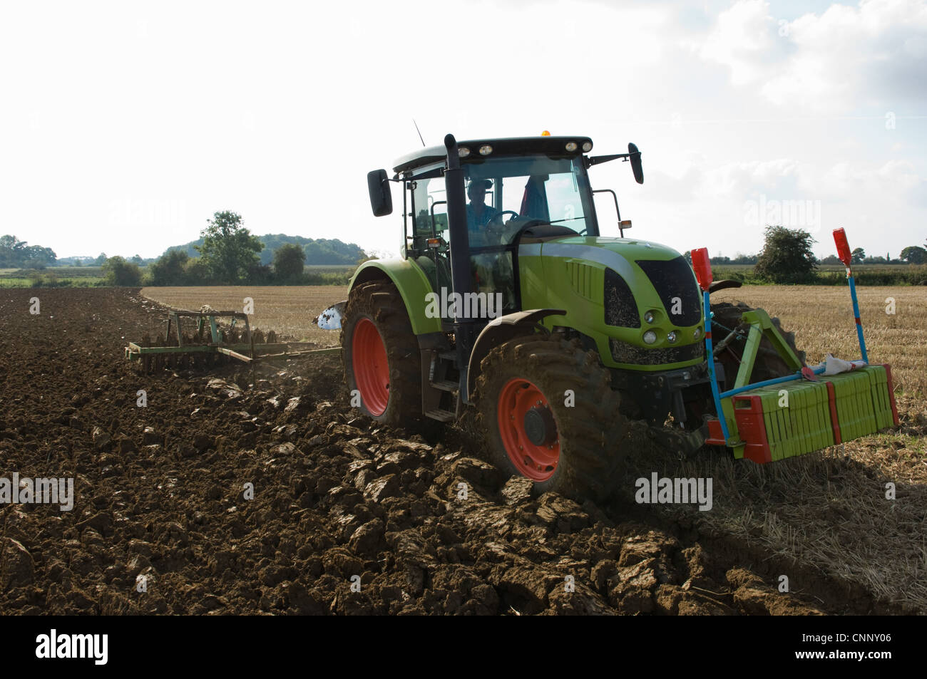 Farmer driving tractor through fields Stock Photo - Alamy
