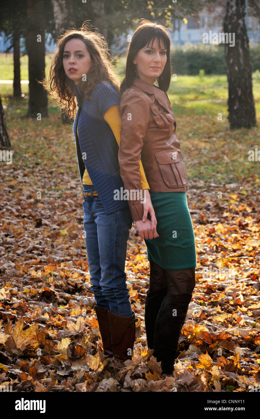 Two young women standing outdoors back to back holding hands Stock ...