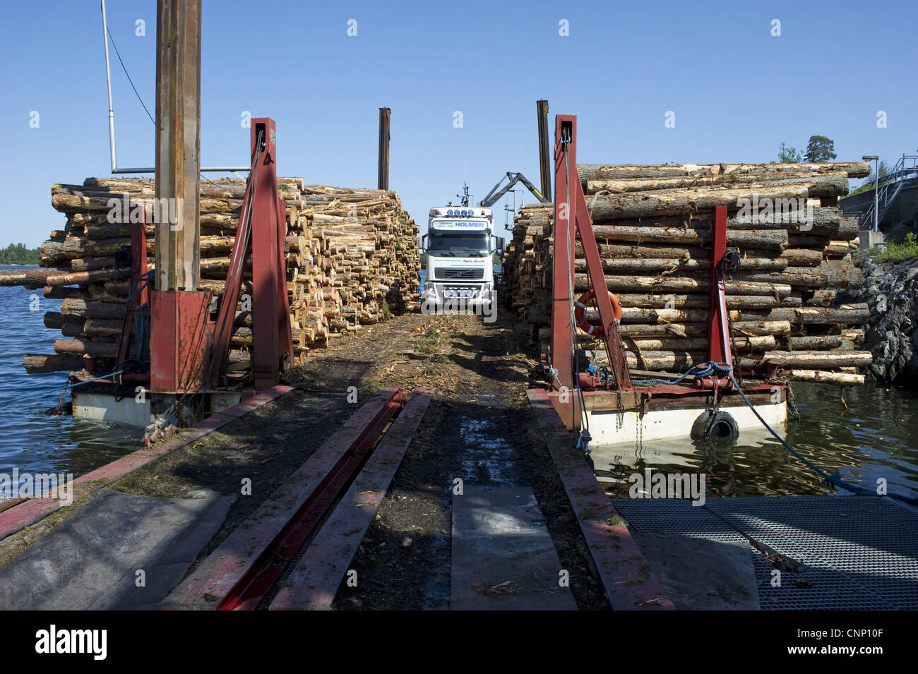 Lorry with grapple loading logs onto timber barge, Archipelago Sea ...
