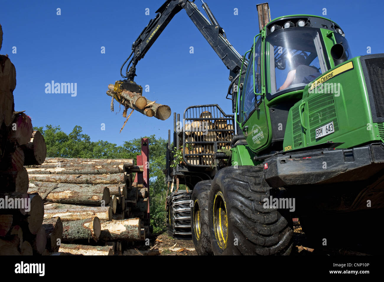 John Deere 1010E Forwarder loading logs onto timber barge, Archipelago ...
