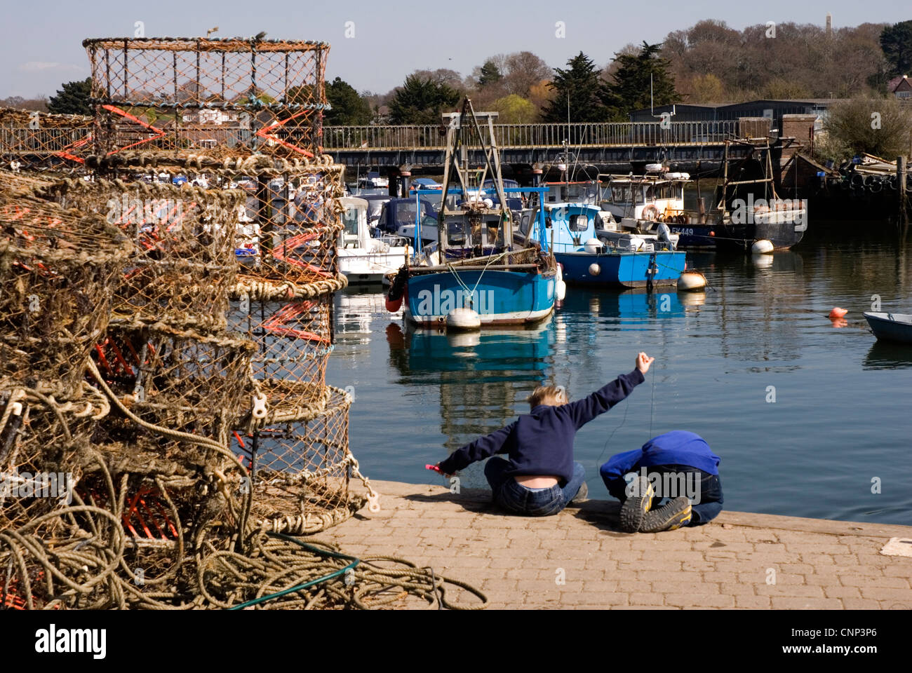 Lymington harbour wall - two small boys fishing for crabs - pulling the ...