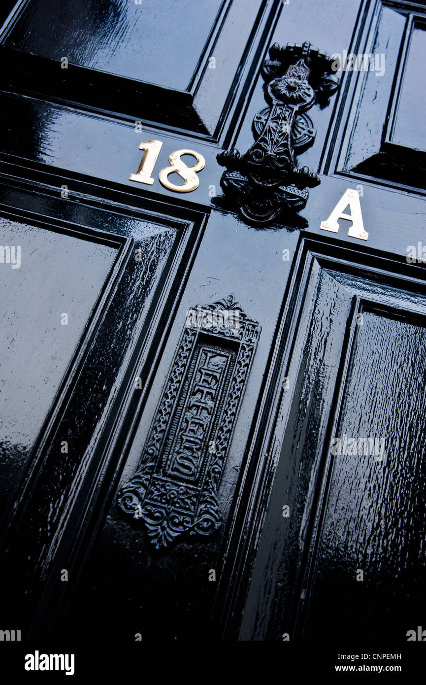 Black painted wooden panelled front door with an ornate iron door ...
