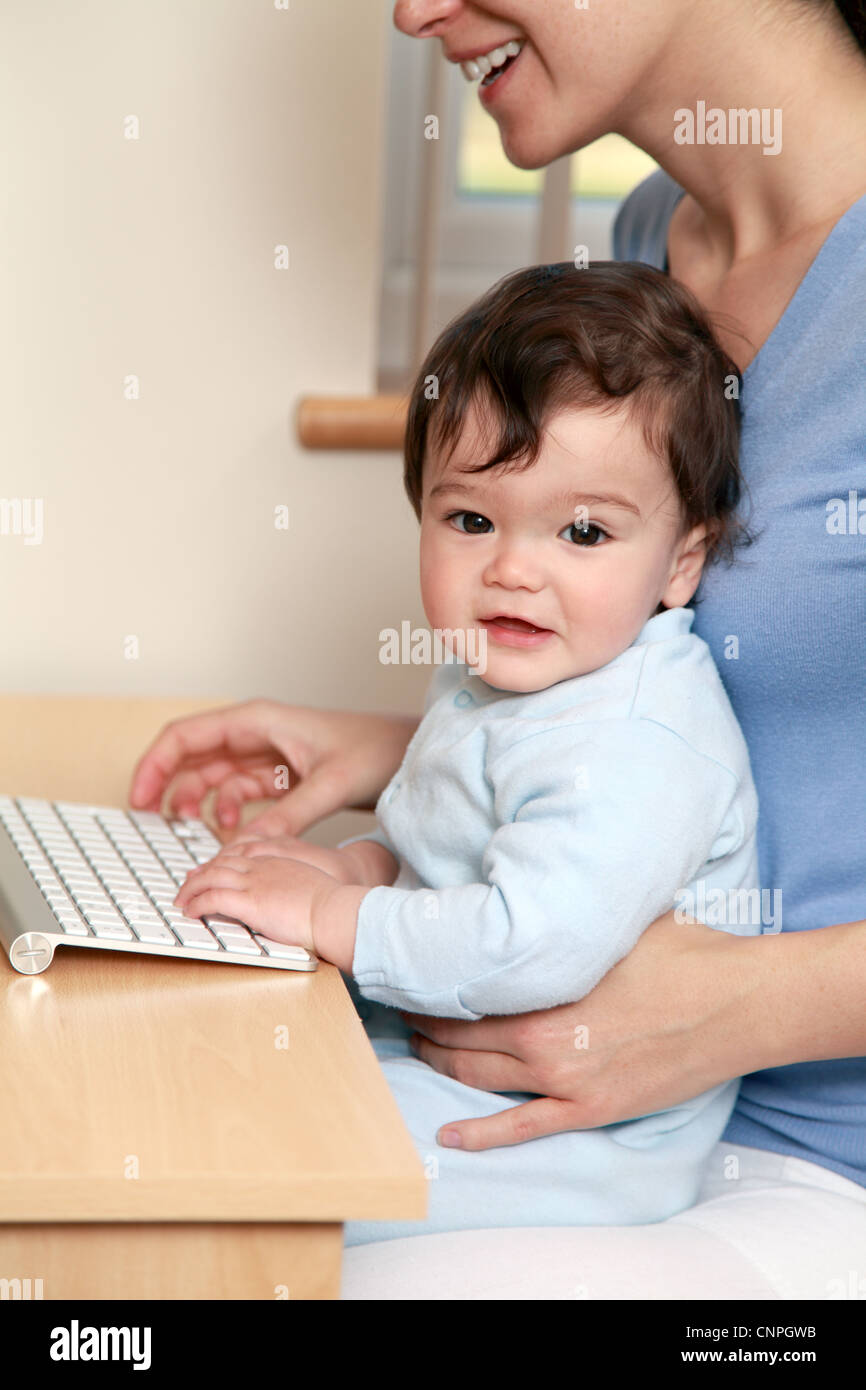 Baby sat on mums lap while she on computer Stock Photo - Alamy