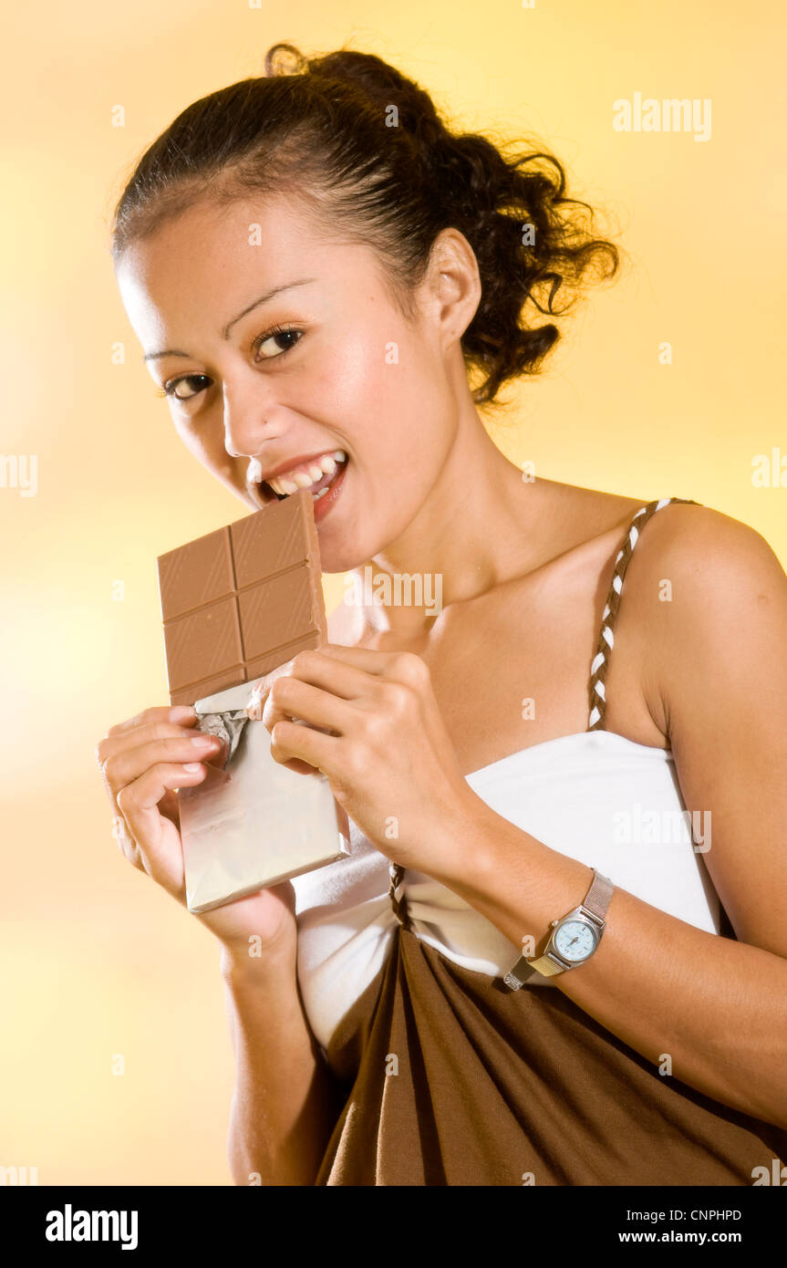 Asian model eating chocolate in studio setting Stock Photo - Alamy