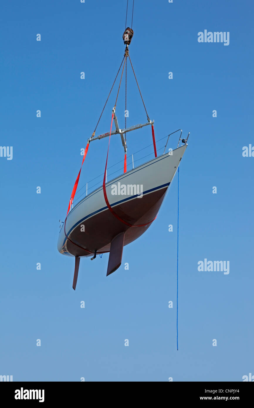 Sailing boat being hoisted into the harbour by a crane for the summer ...