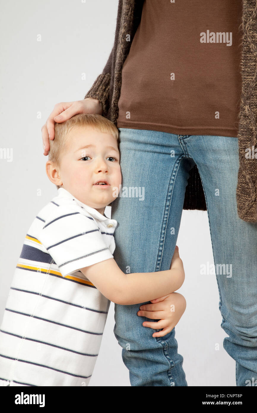 Cute blond boy hugging his mother's leg Stock Photo - Alamy
