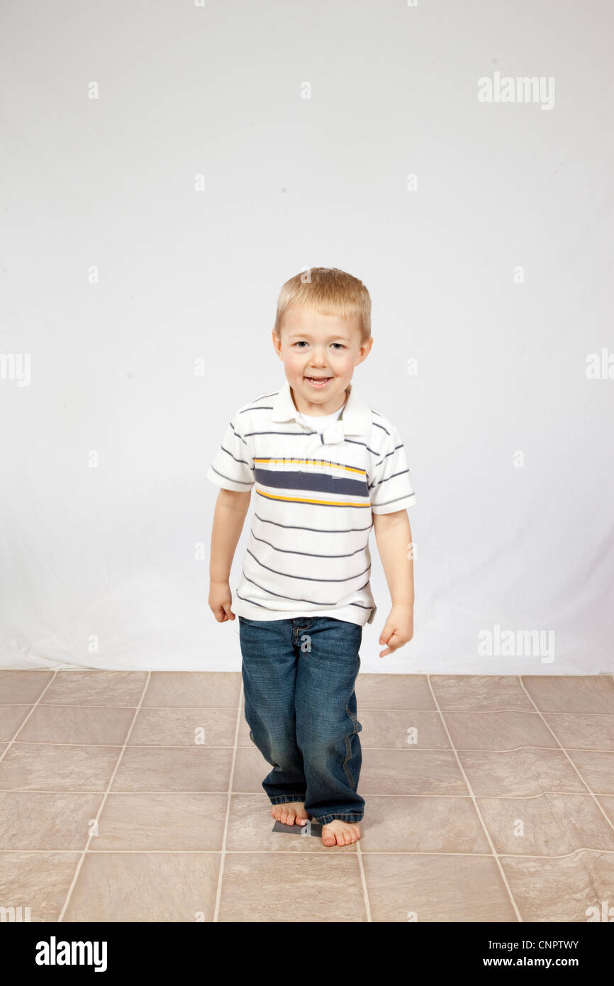 Cute little blond boy wearing blue jeans and a striped shirt, walking ...