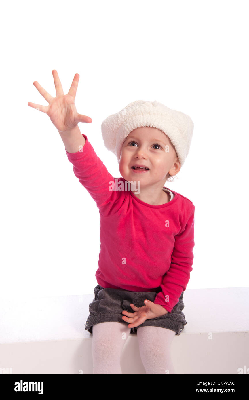little girl looking up trying to grab something on white background ...