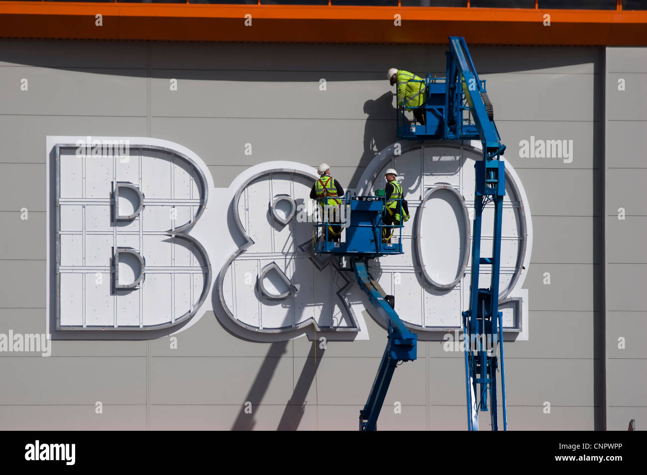 Workmen in a cherry picker erecting a B&Q sign at a new DIY store in ...