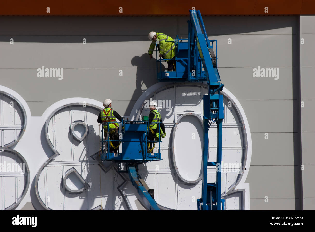 Workmen in a cherry picker erecting a B&Q sign at a new DIY store in ...