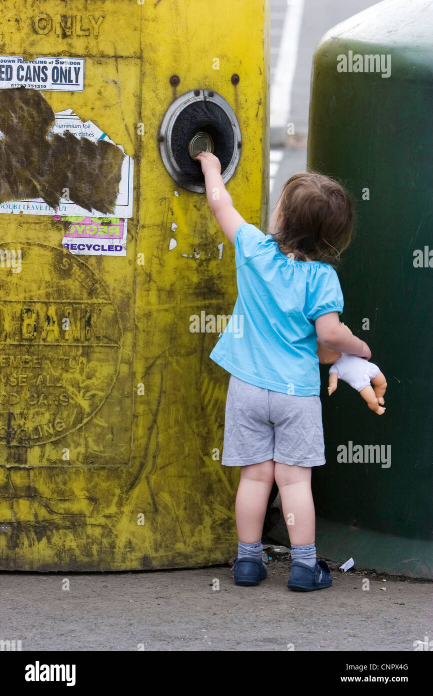 Children recycling metal tin cans and glass bottles at the recycling ...