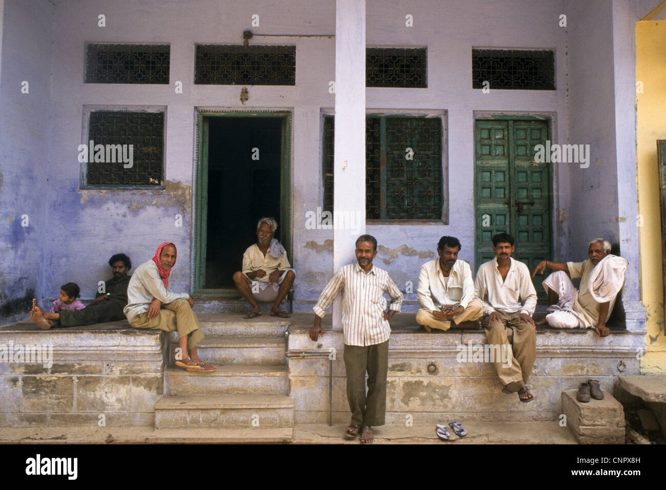 Group of Indian men sitting at the entrance to a house at the ancient ...