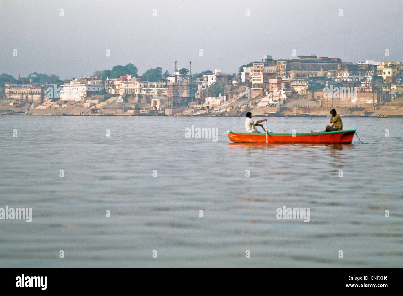 Red boat sailing the river ganges at the ancient Indian city of Benares ...