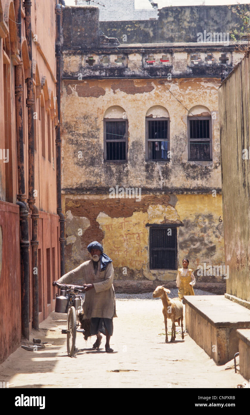 Street scene with an old indian man carrying a bicycle at the ancient ...