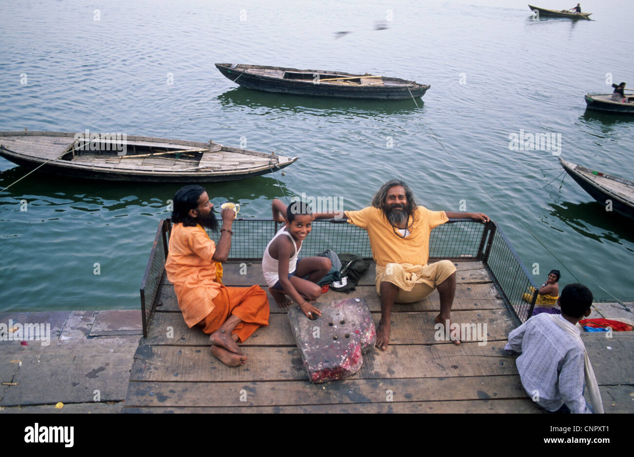 Group of people sitting next to the Ganges river at the ancient Indian ...