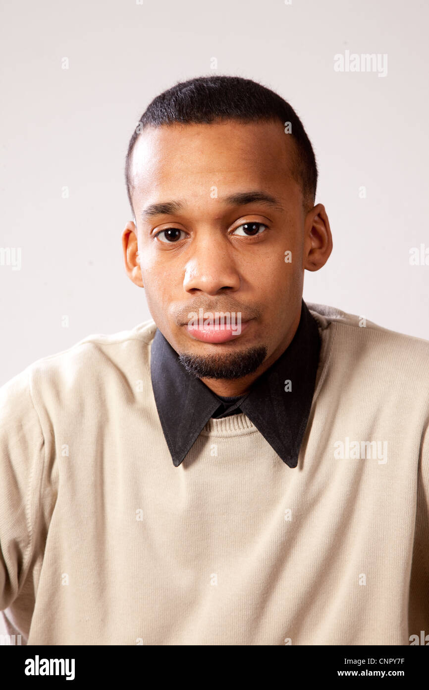 Handsome young black man with pensive expression looking at the camera ...