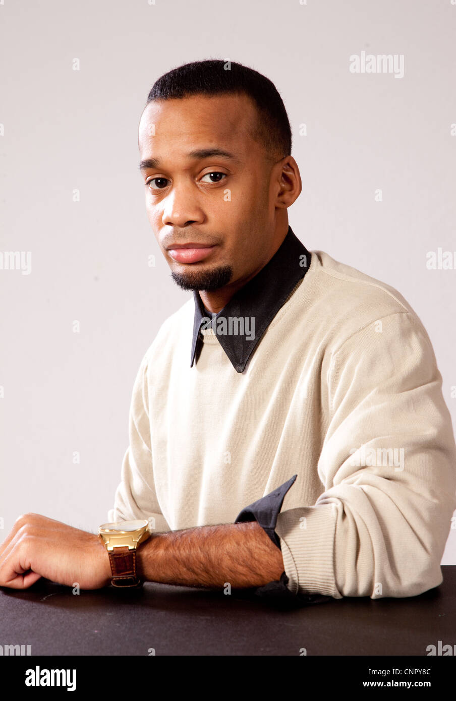 Handsome young black man with pensive expression looking at the camera ...