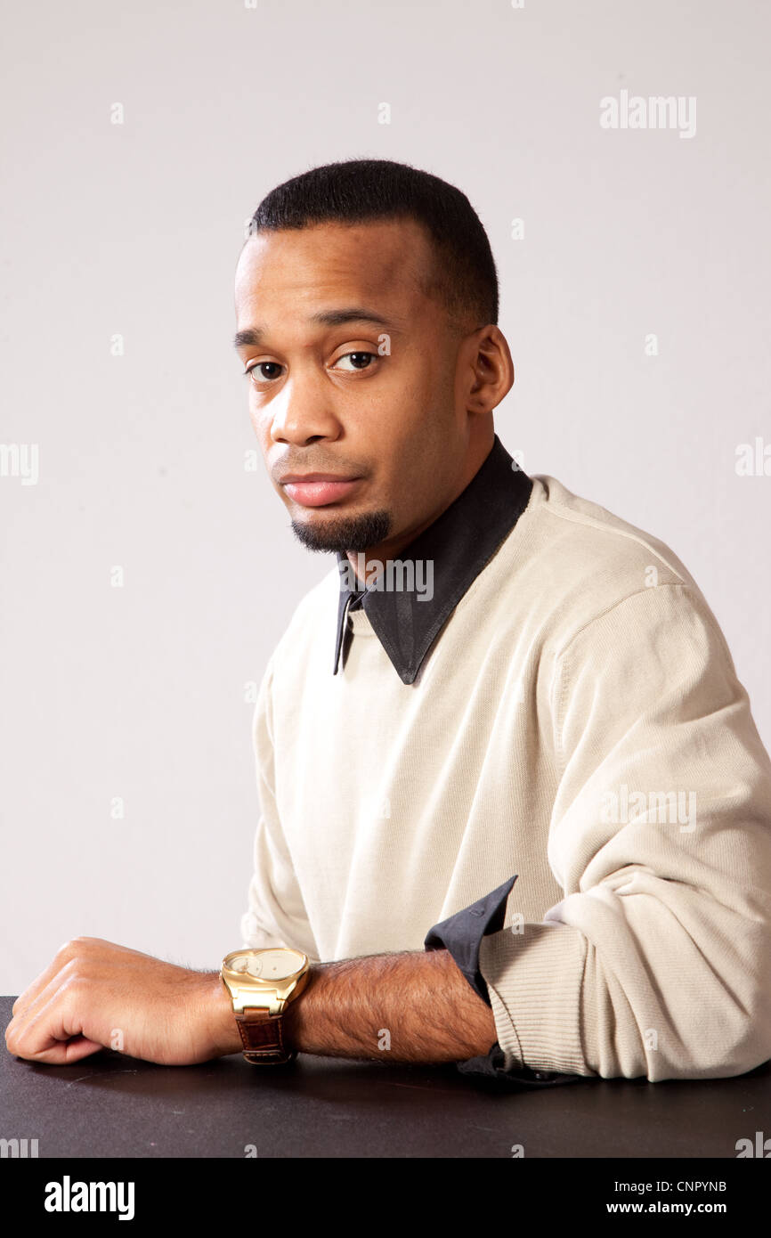 Handsome young black man with pensive expression looking at the camera ...