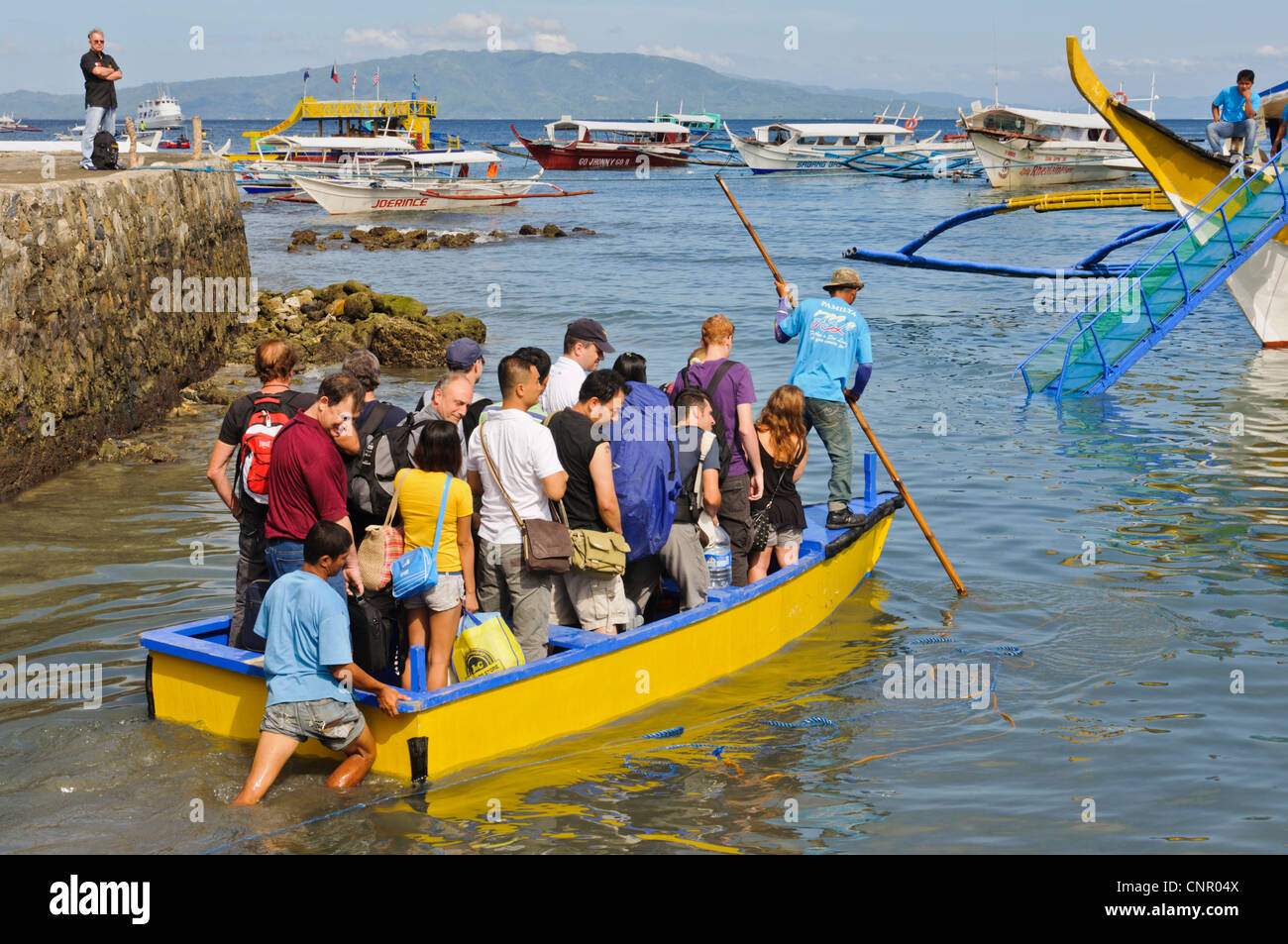 Tourists boarding commuter ferry boat from an overcrowded small boat ...