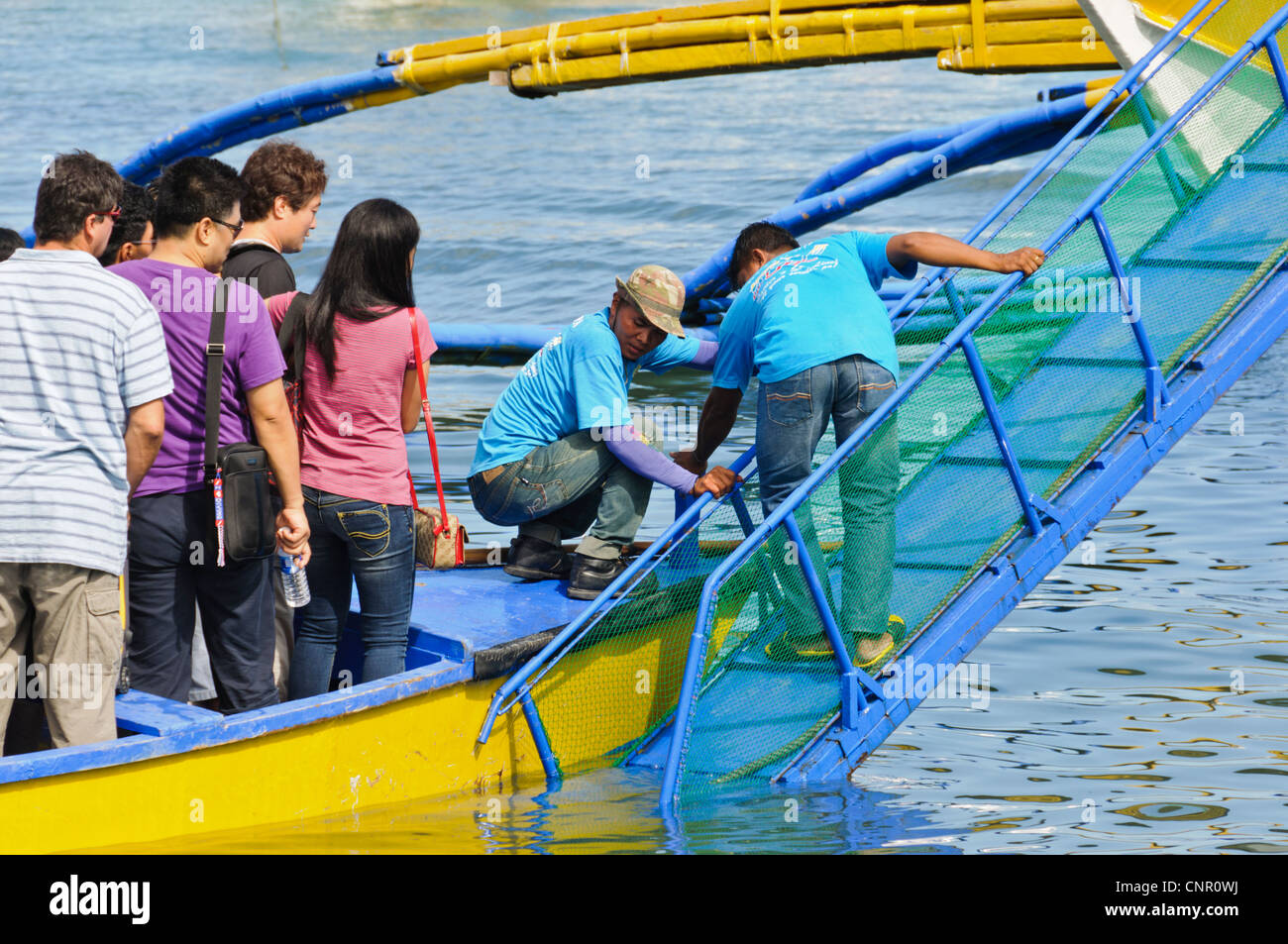 Tourists boarding commuter ferry boat from an overcrowded small boat ...
