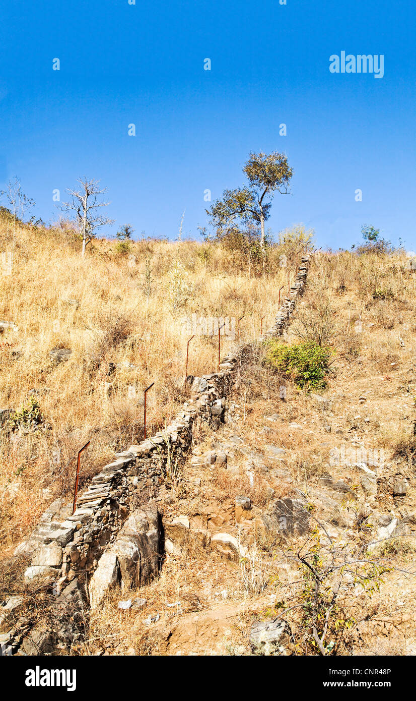 Arid land Rajasthan India, dry stone wall going over the hill with ...