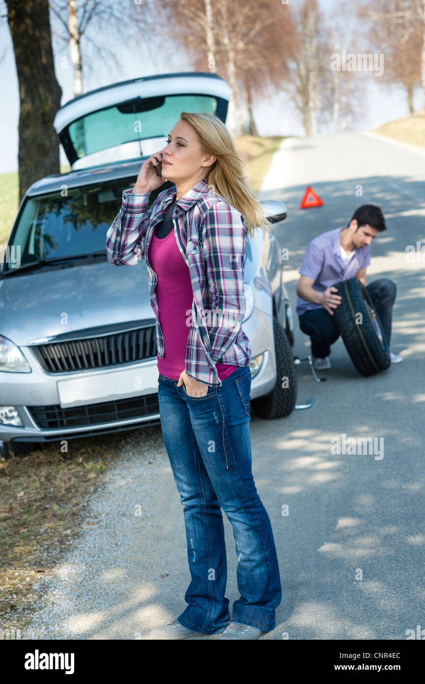 Car trouble woman calling road assistance man change broken wheel Stock ...
