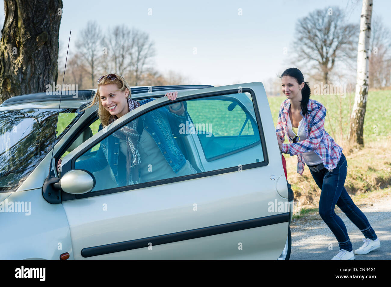 Vehicle breakdown two young women pushing car down the road Stock Photo ...