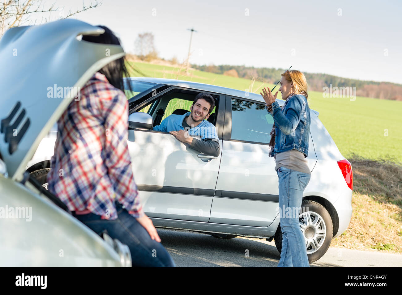 Car troubles two woman friends asking help young man Stock Photo - Alamy