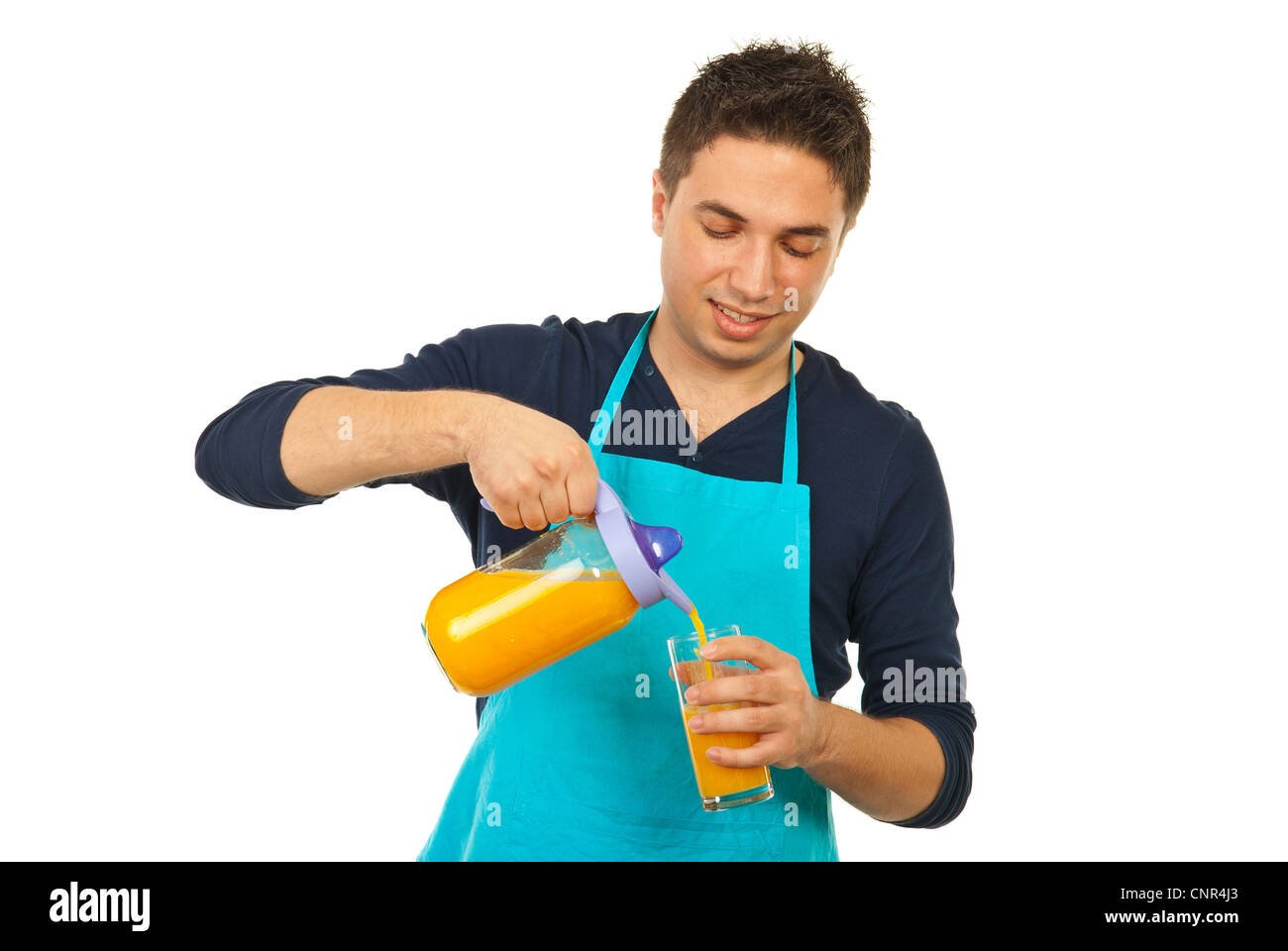 Happy chef man with blue apron pouring orange juice in a glass isolated ...