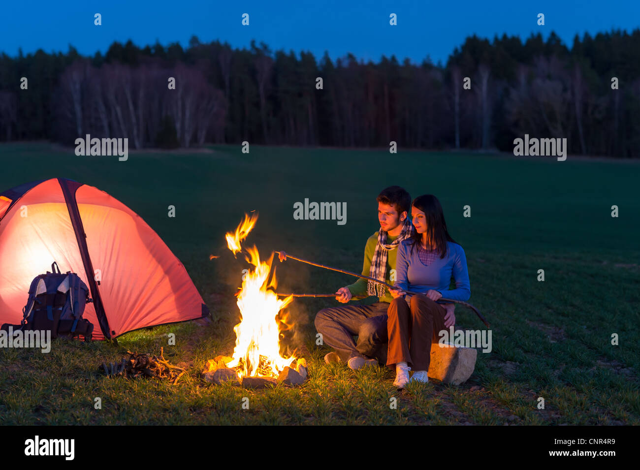 Camping night couple cook by campfire backpack in romantic countryside ...
