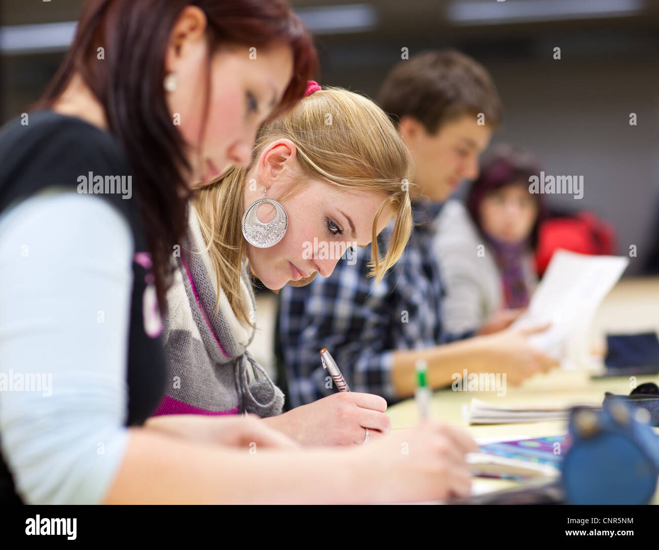 pretty female college student sitting in a classroom full of students ...