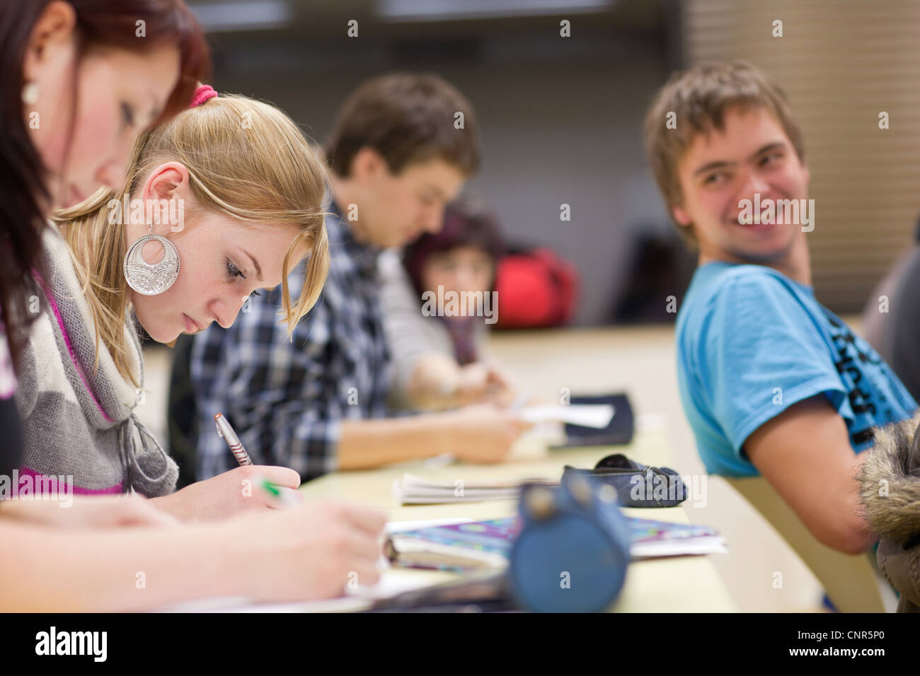 pretty female college student sitting in a classroom full of students ...
