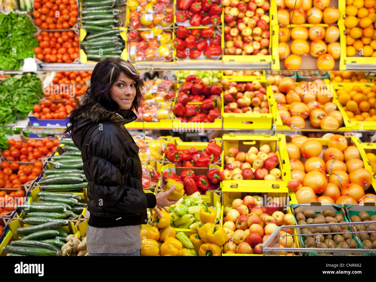 Beautiful young woman buying fruits and vegetables at a produce ...
