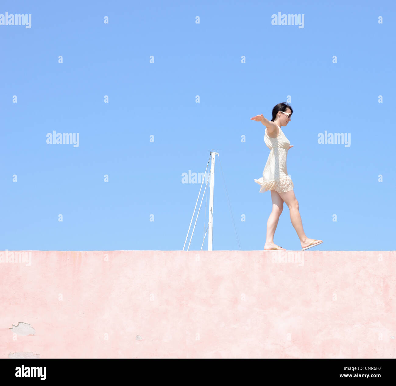 Woman balancing on wall Stock Photo - Alamy