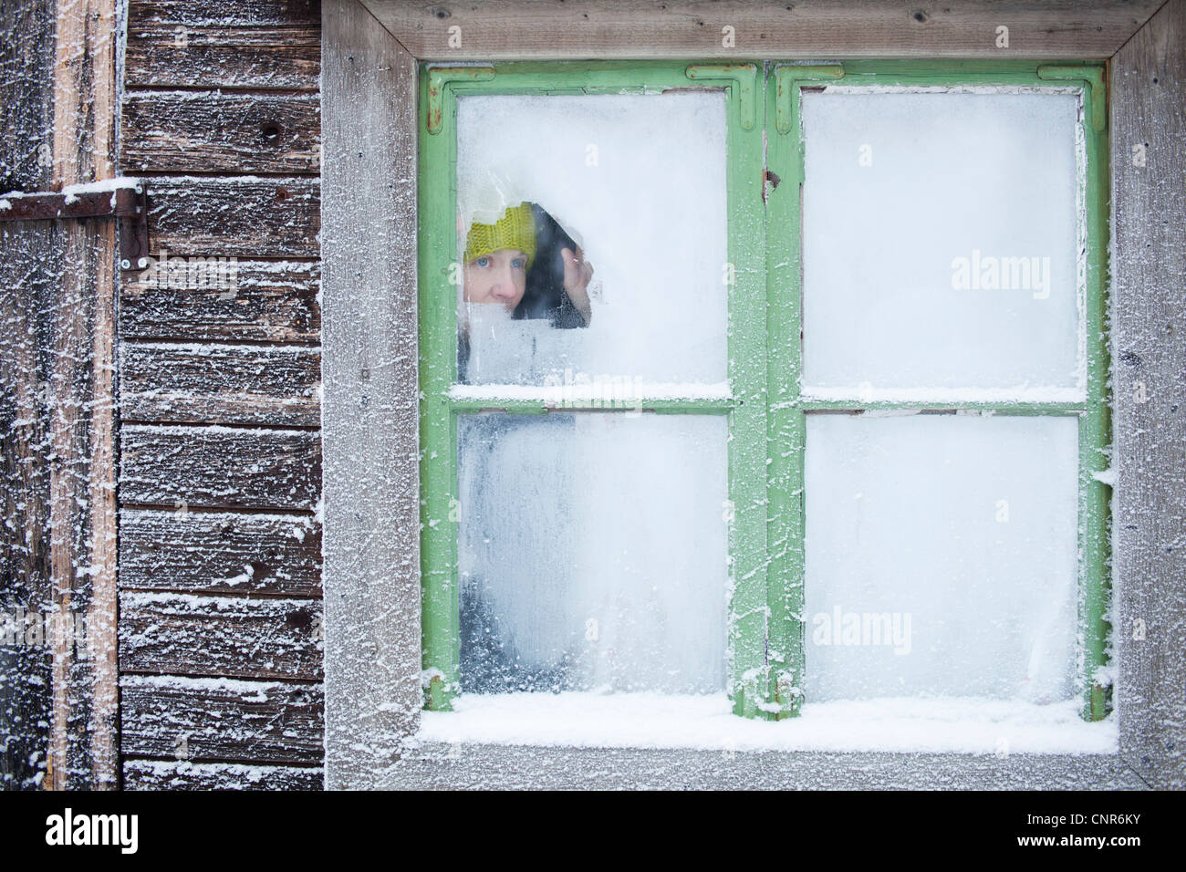 Woman peering out frosty window Stock Photo - Alamy