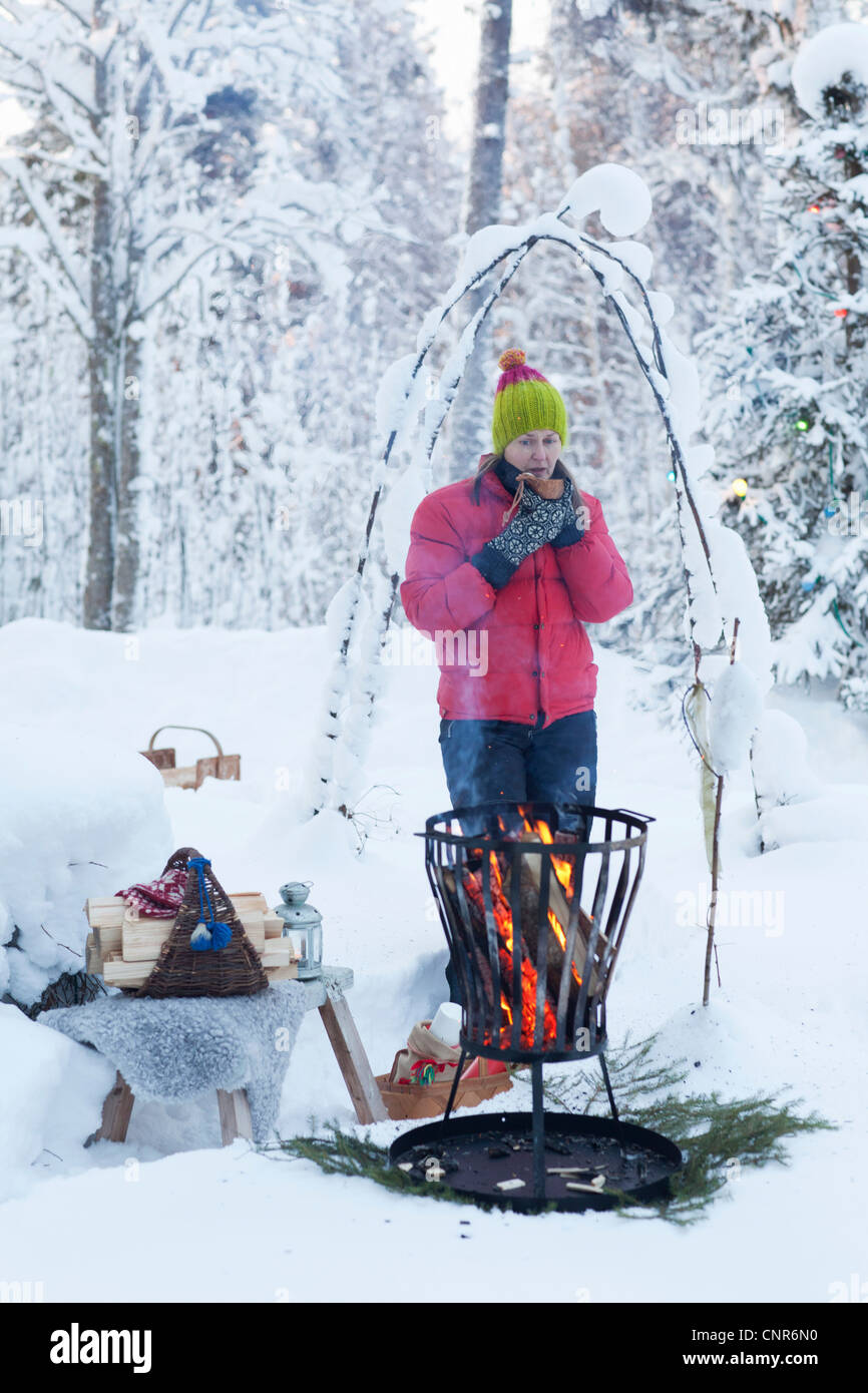 Woman drinking coffee by firepit in snow Stock Photo - Alamy