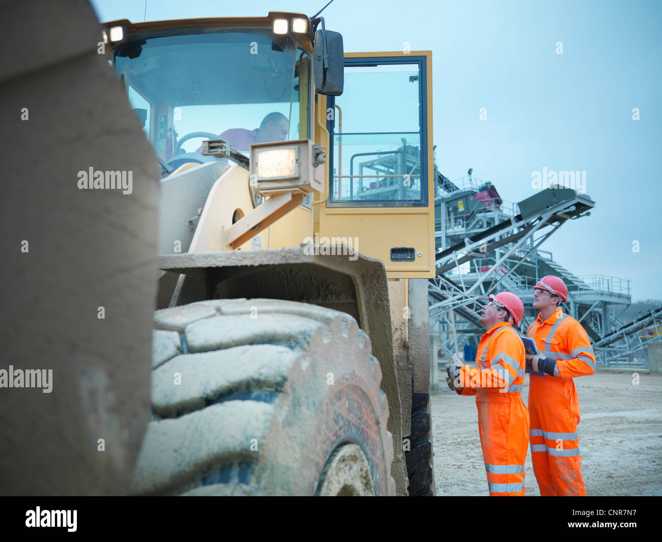 Workers talking to digger driver on site Stock Photo - Alamy