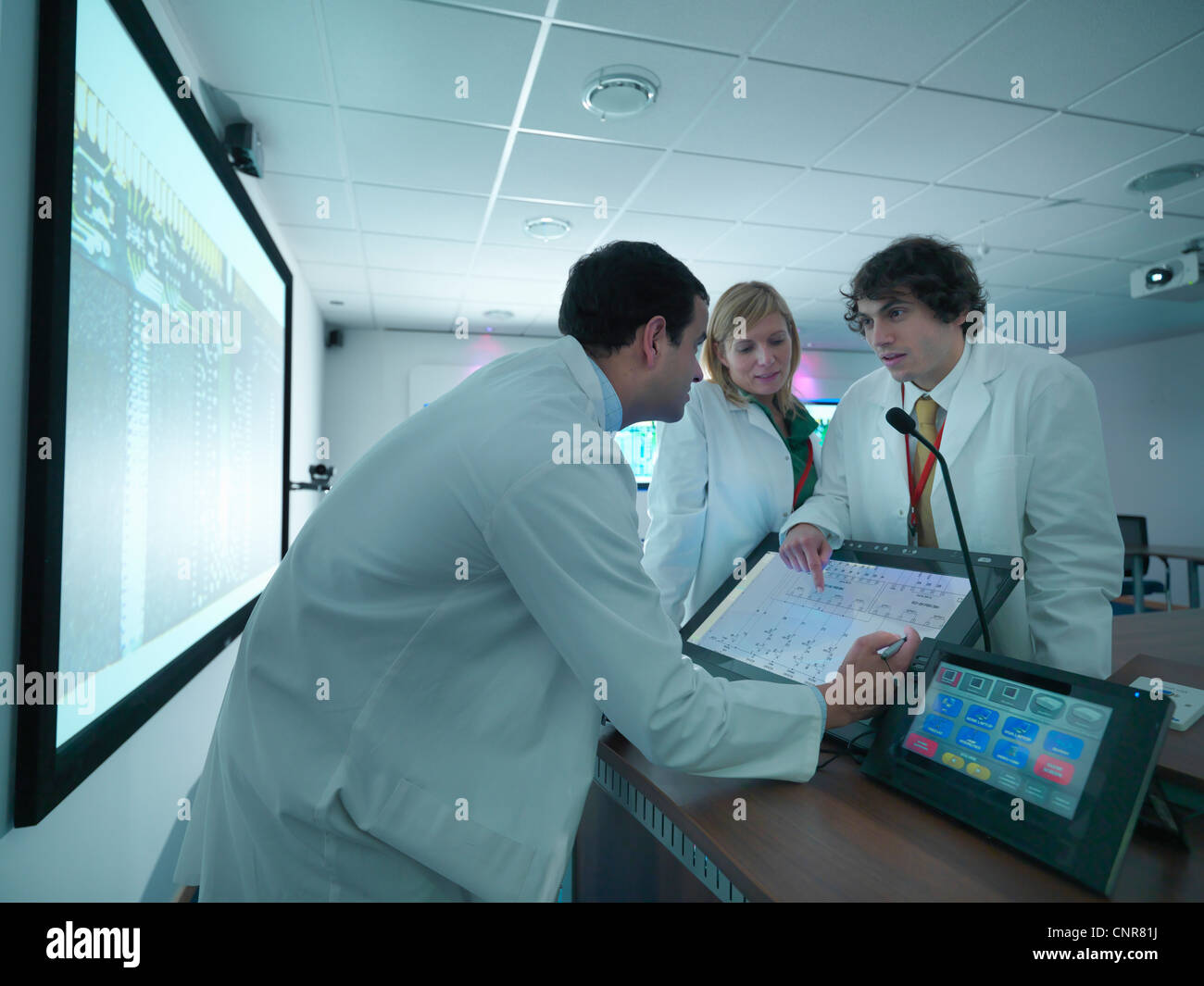 Three scientists standing discussing diagram hi-res stock photography ...