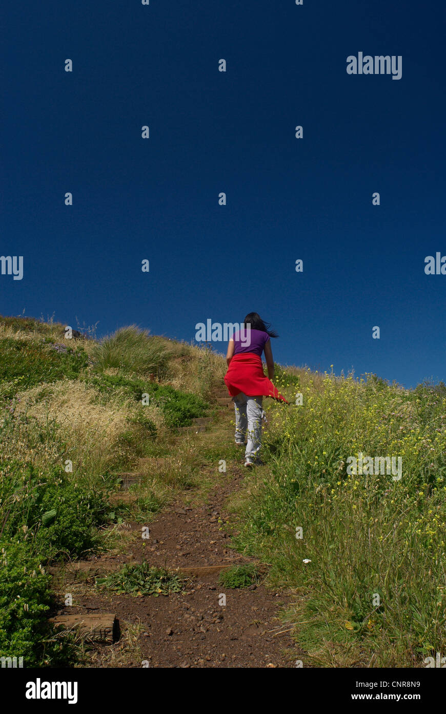Woman hiking up rural hill Stock Photo - Alamy